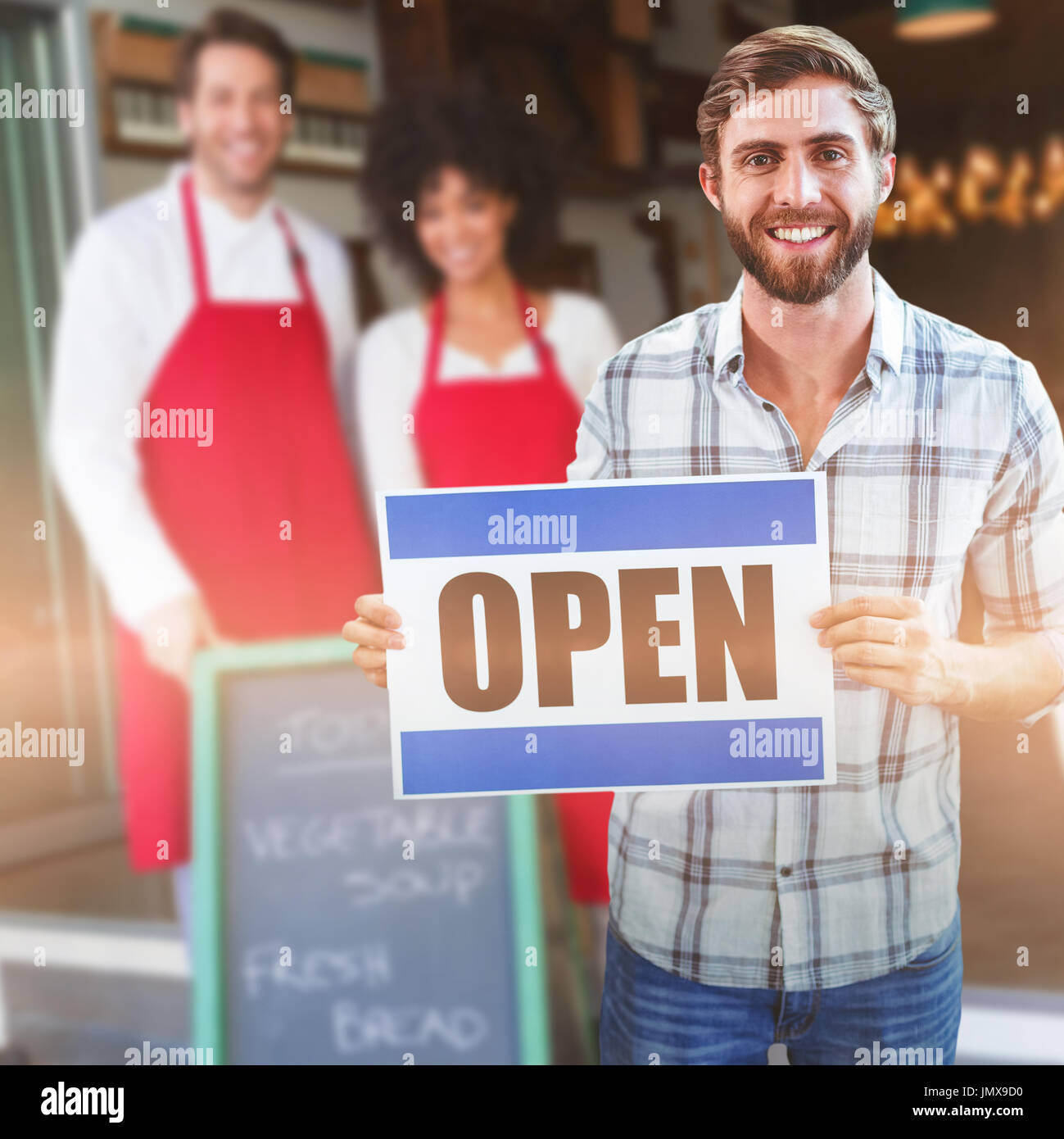 Portrait of male owner holding open sign against smiling colleagues ...