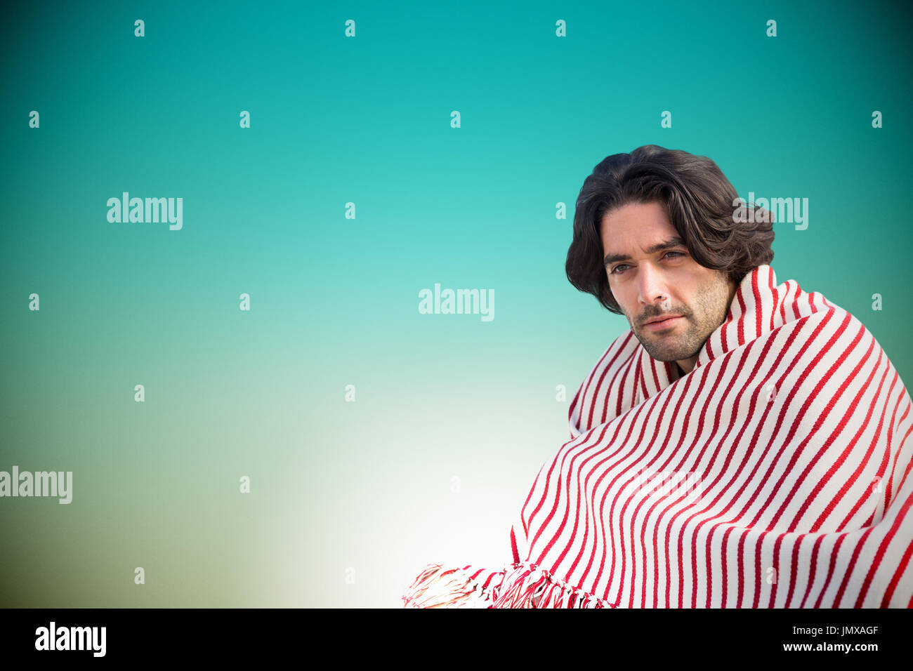 Thinking man with blanket against blue green background Stock Photo - Alamy