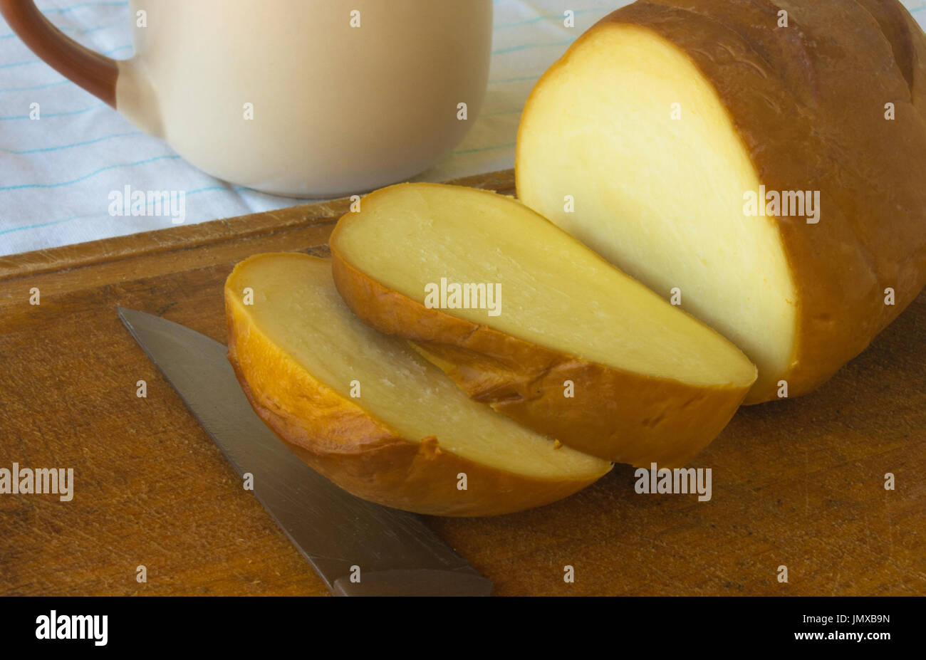 cut head of traditional Adygei cheese handmade with knife and a Cup of ...