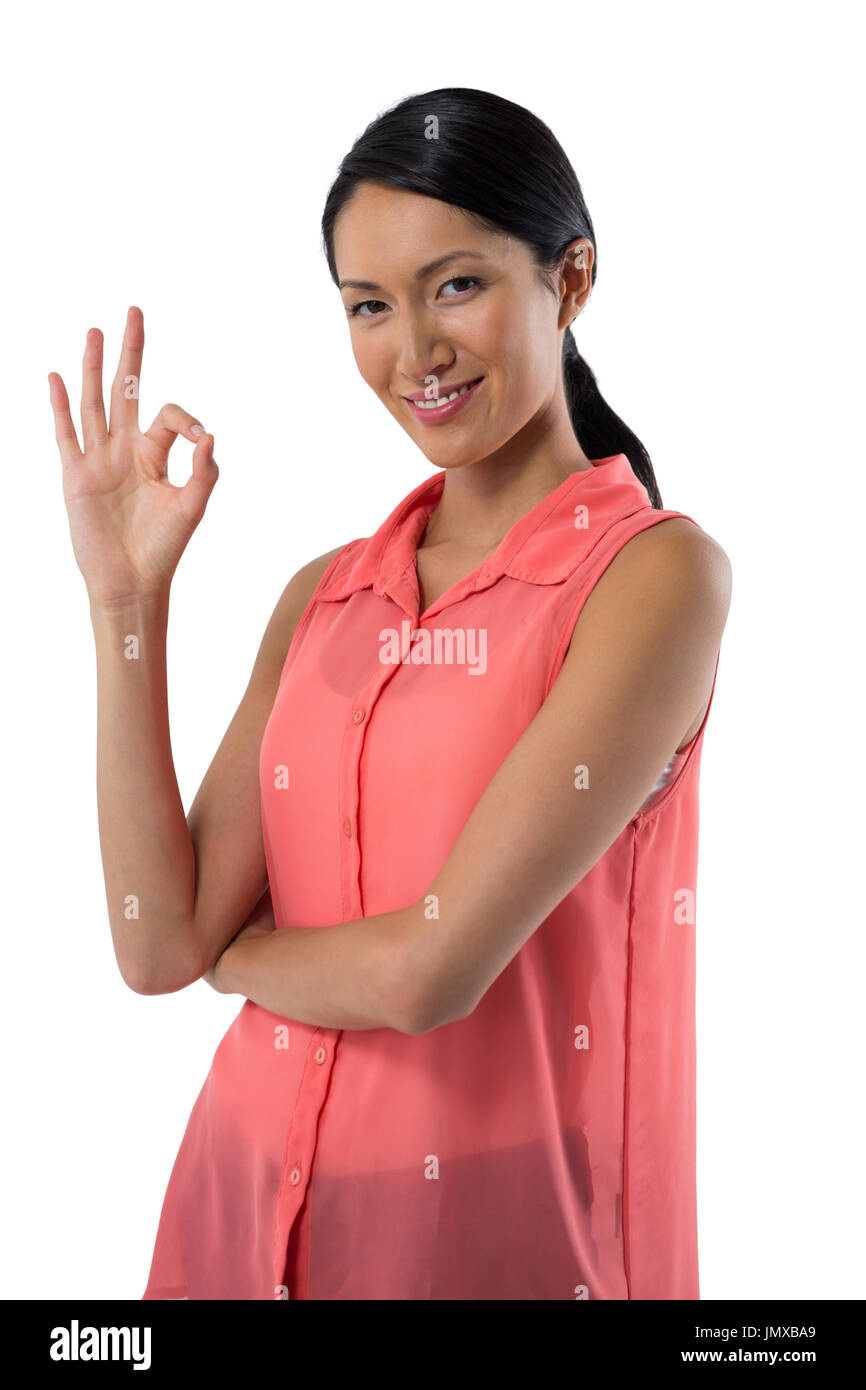 Portrait of smiling woman gesturing okay hand sign against white ...