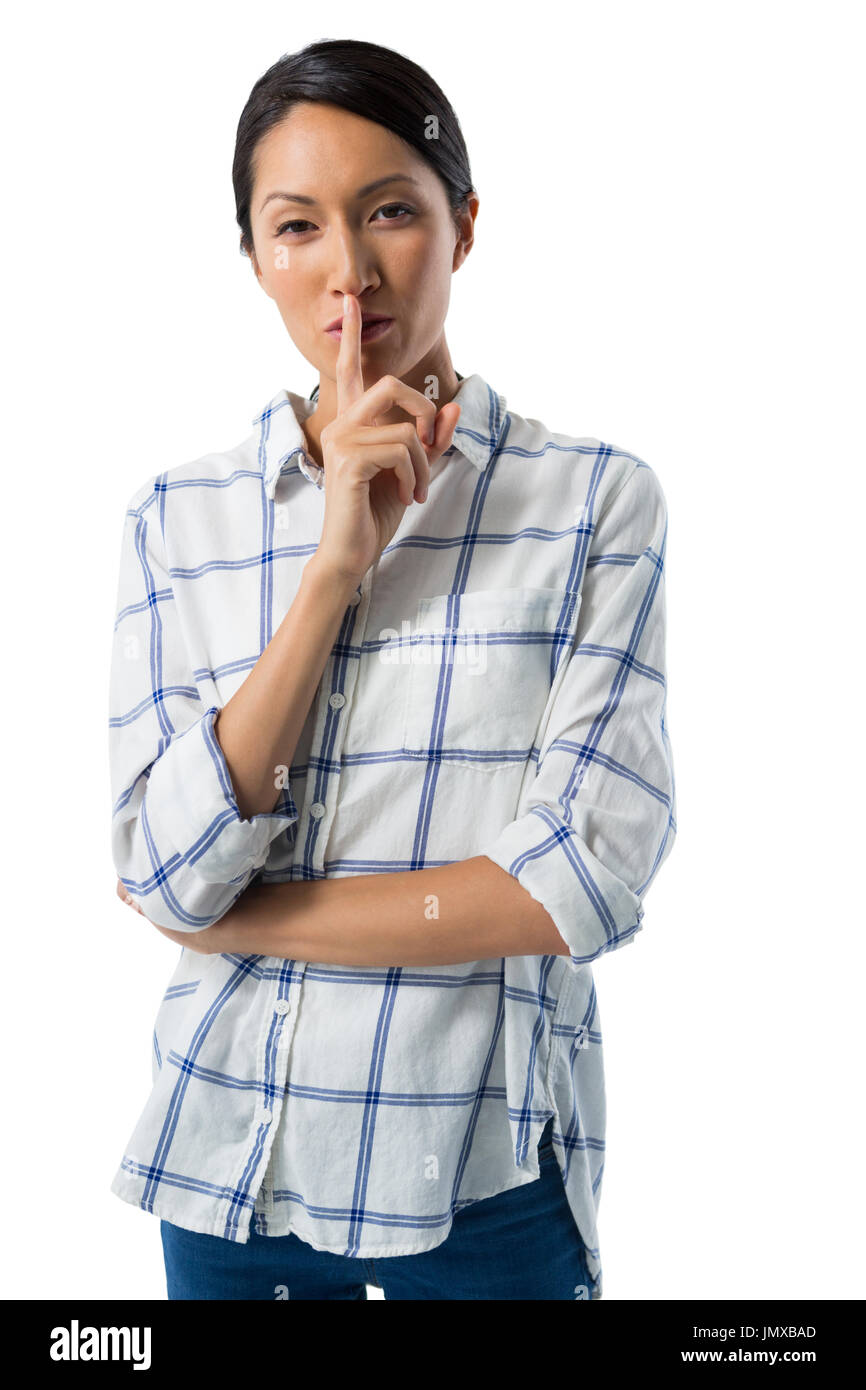 Portrait of woman standing with finger on lips against white background ...