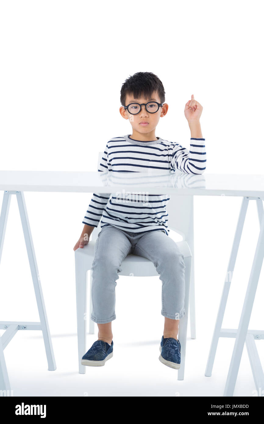 Portrait of boy sitting on chair against white background Stock Photo ...