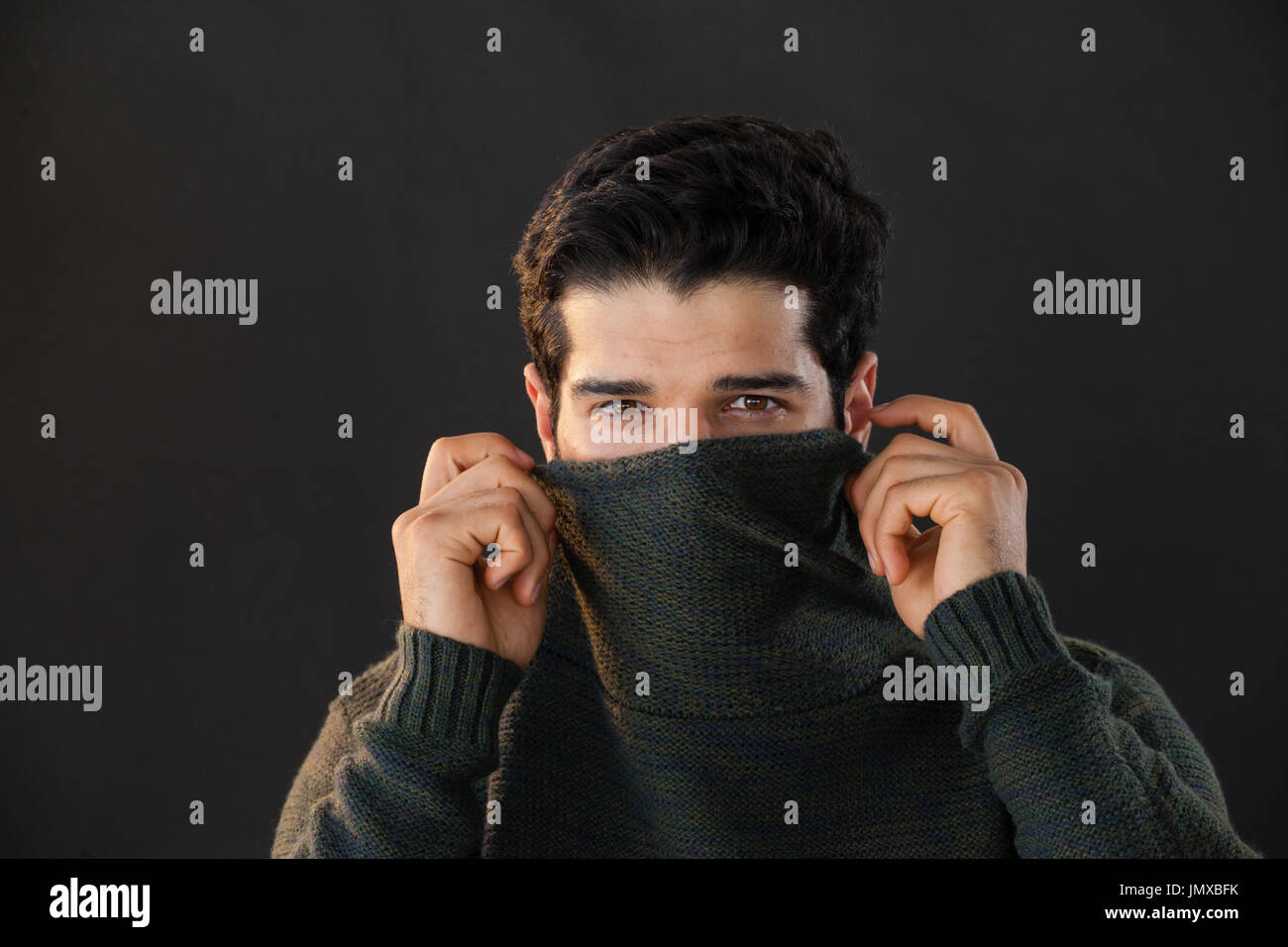Portrait of man hiding face from scarf against white background Stock ...