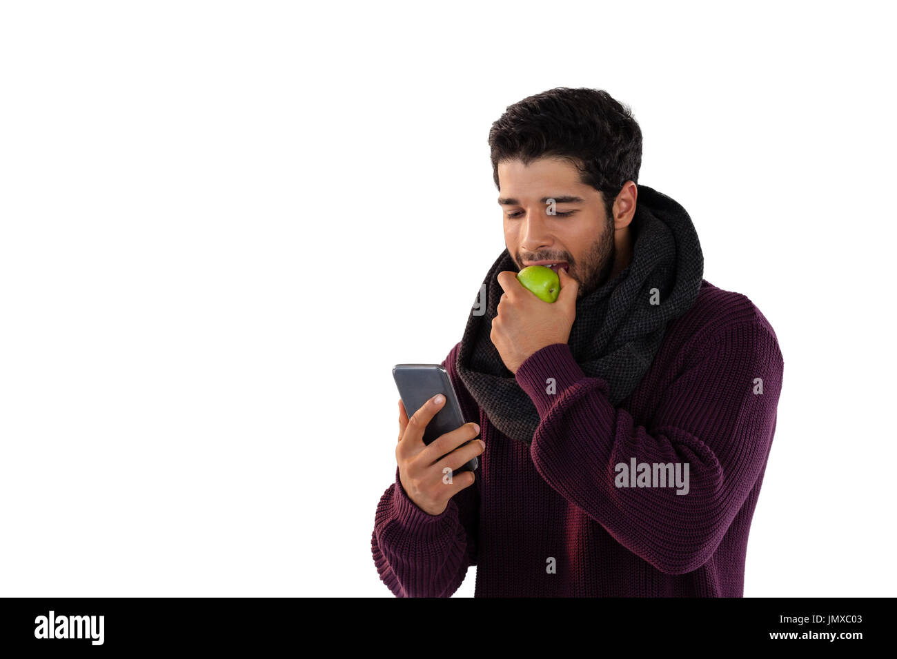 Man eating apple while using mobile phone against white background ...