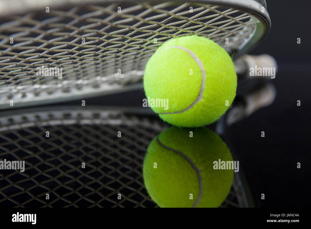 Close up of tennis racket on ball with reflection against black ...