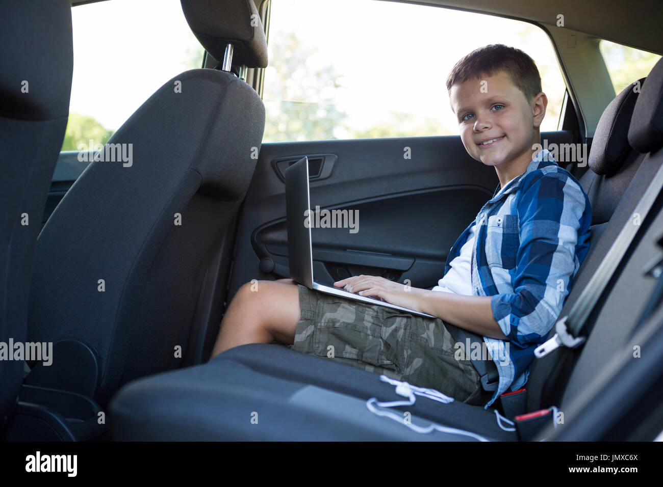 Portrait of teenage boy using laptop in the back seat of car Stock ...