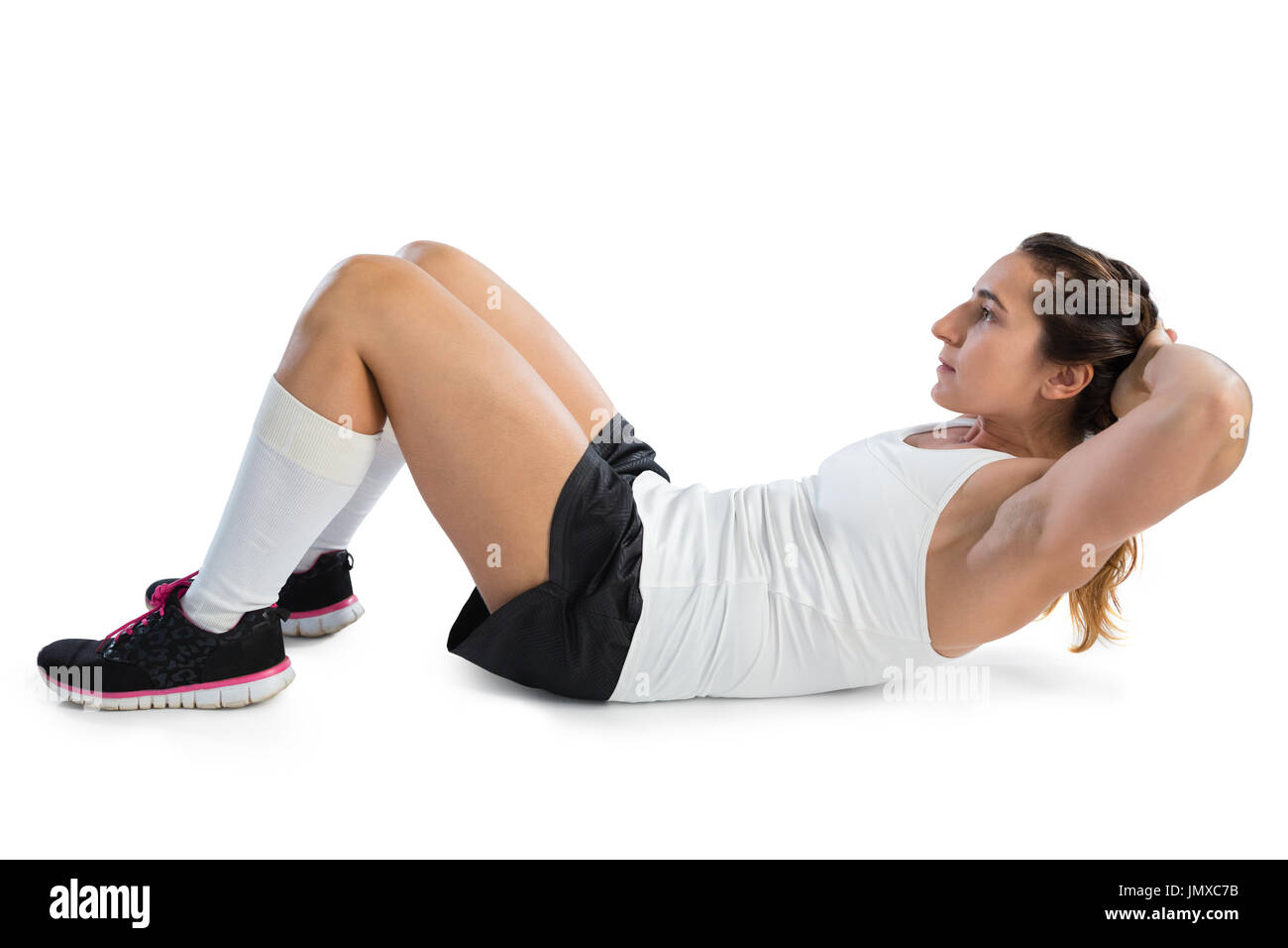 Side view of female athlete practicing sit ups against white background ...