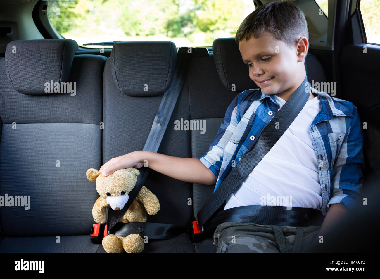 Happy teenage boy sitting with teddy bear in the back seat of car Stock ...