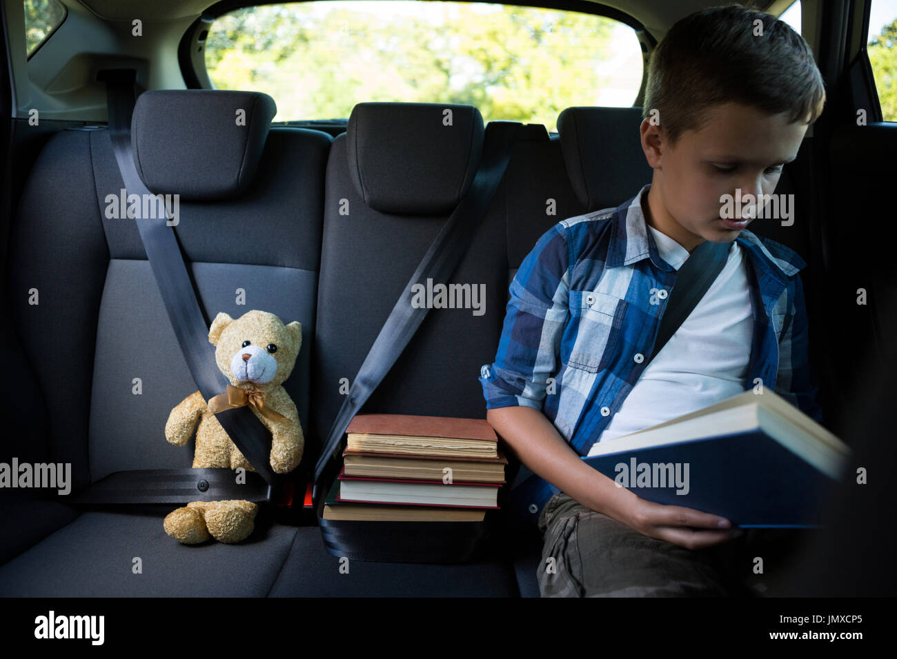 Teenage boy reading book in the back seat of car Stock Photo - Alamy