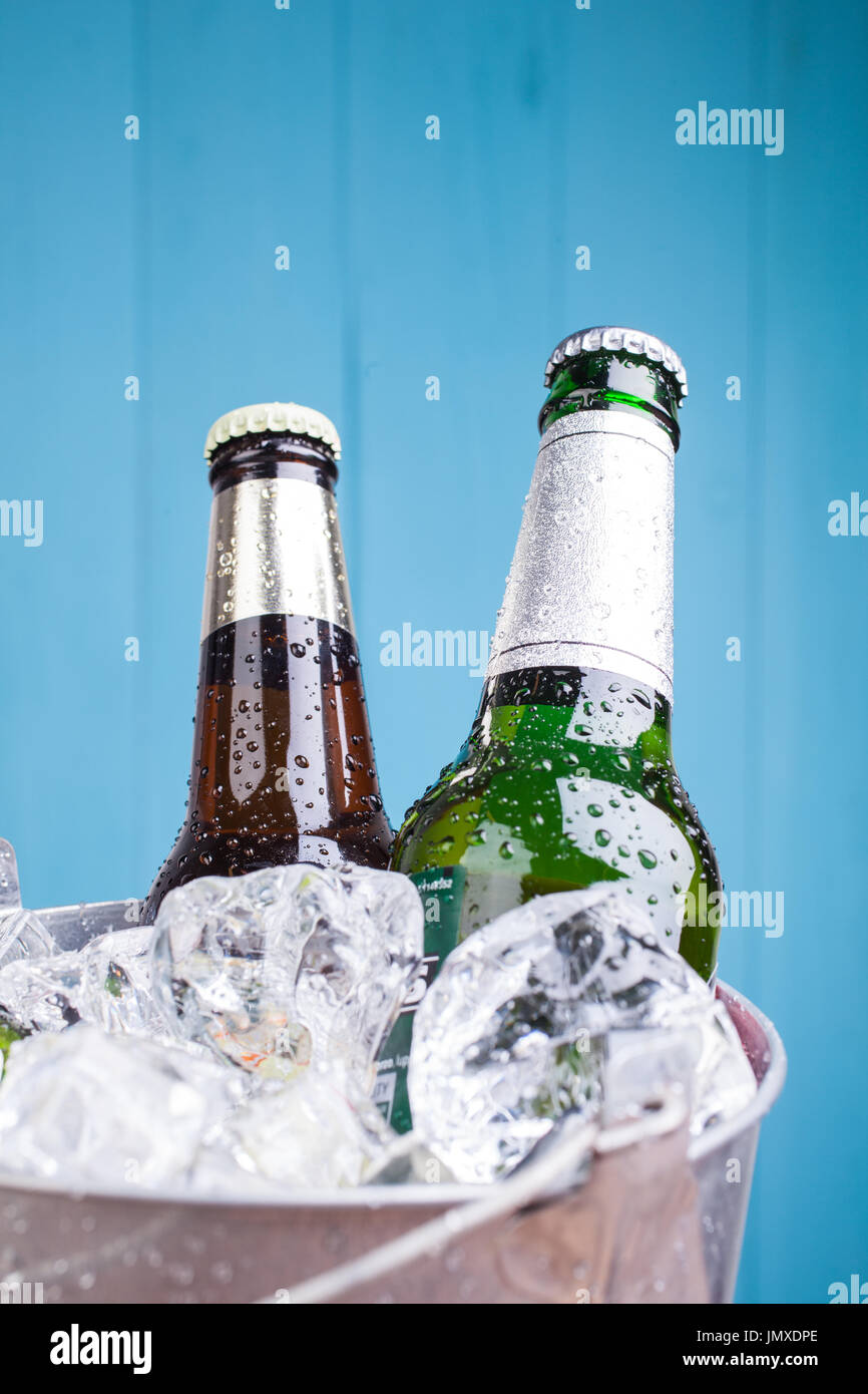 Three unopened bottles of beer inside metal bucket filled with iced ...