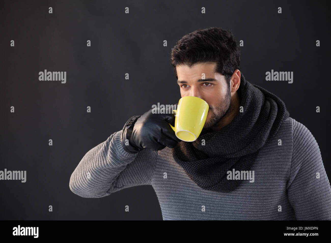 Thoughtful man having a mug of coffee against black background Stock ...
