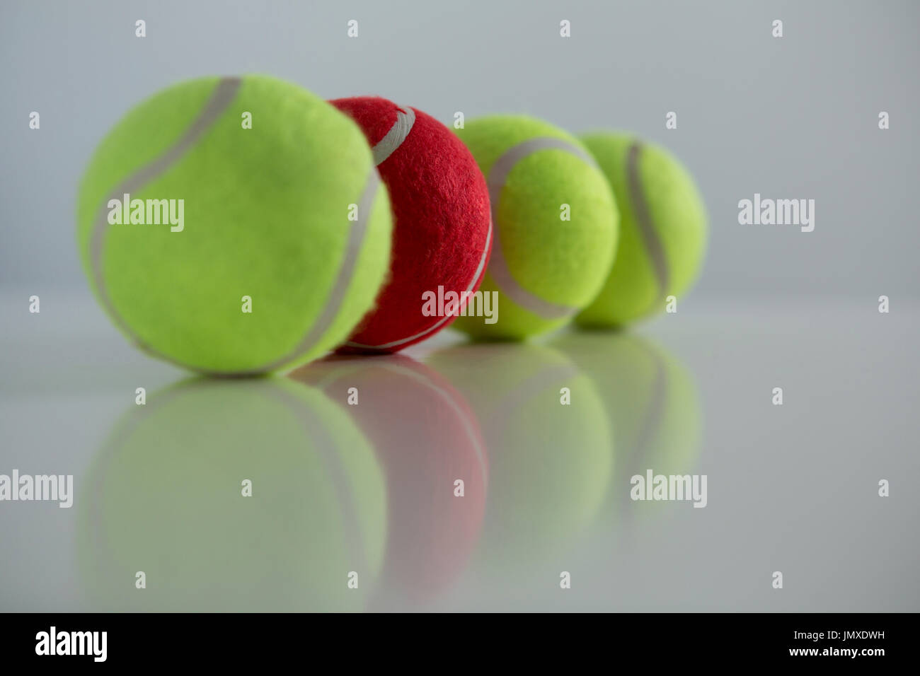 Red and fluorescent tennis ball arranged in row against white ...