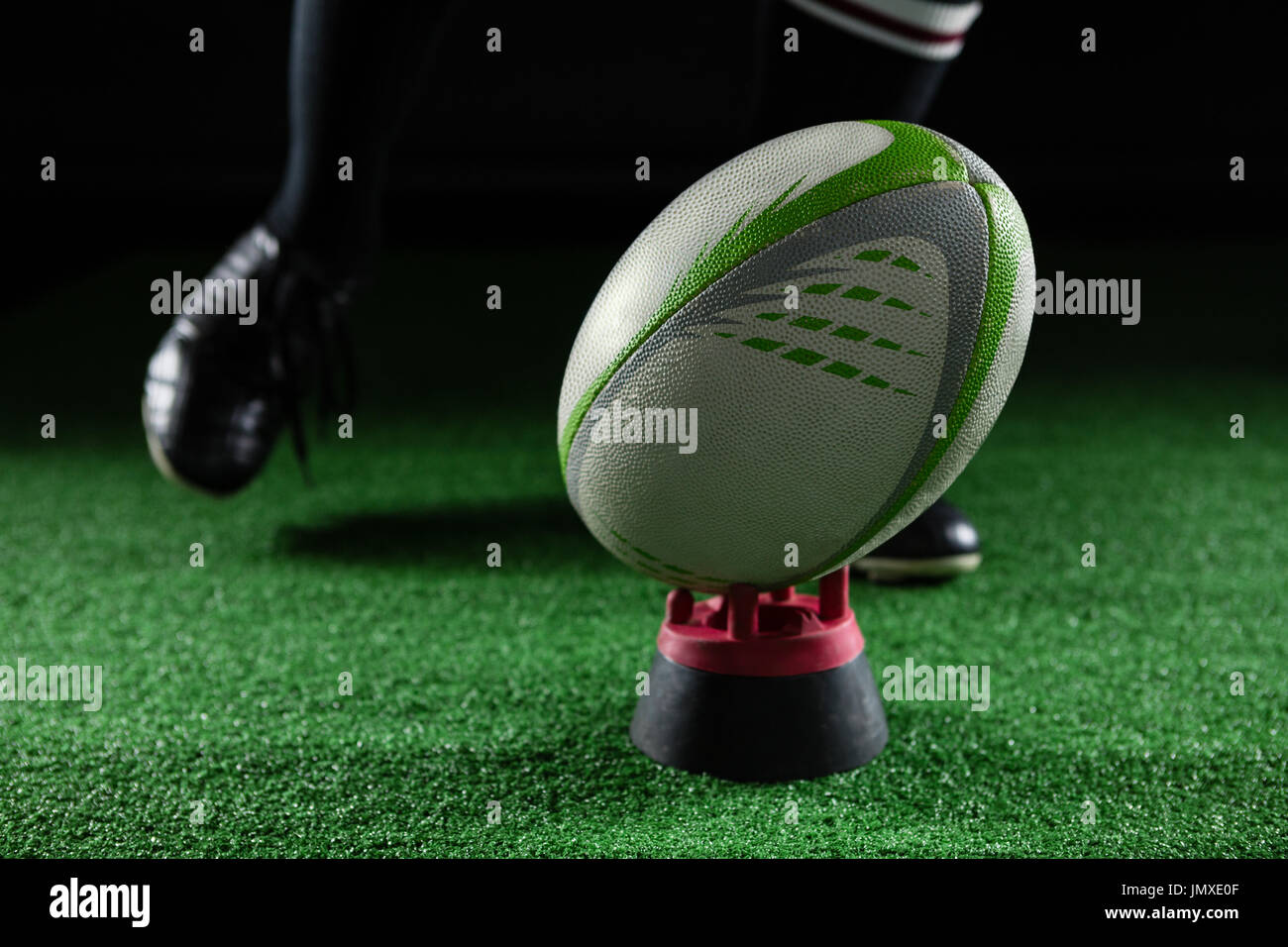 Low section of male athlete kicking rugby ball on tee while playing ...