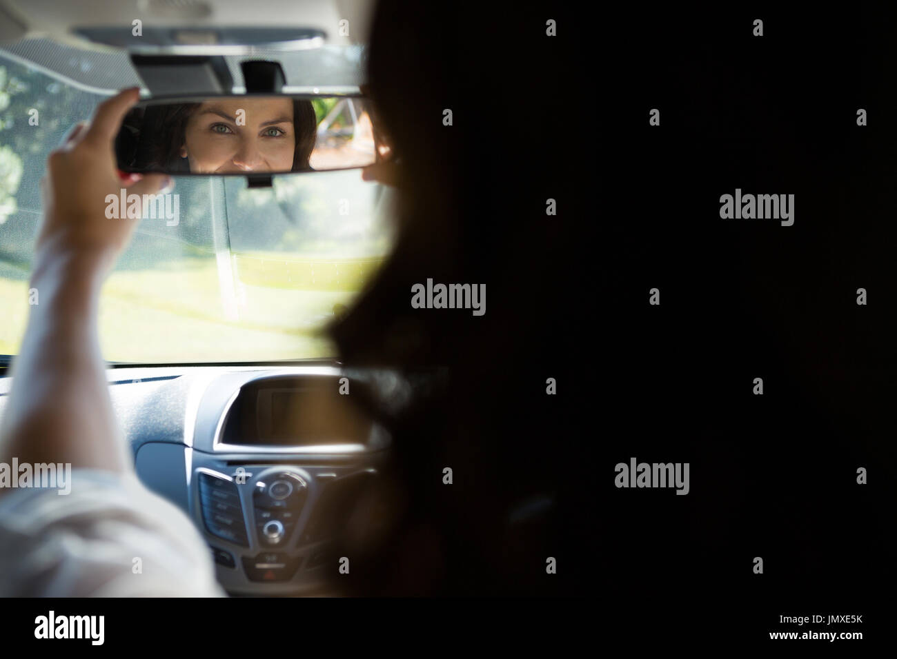 Woman looking into rear view mirror while driving a car Stock Photo - Alamy