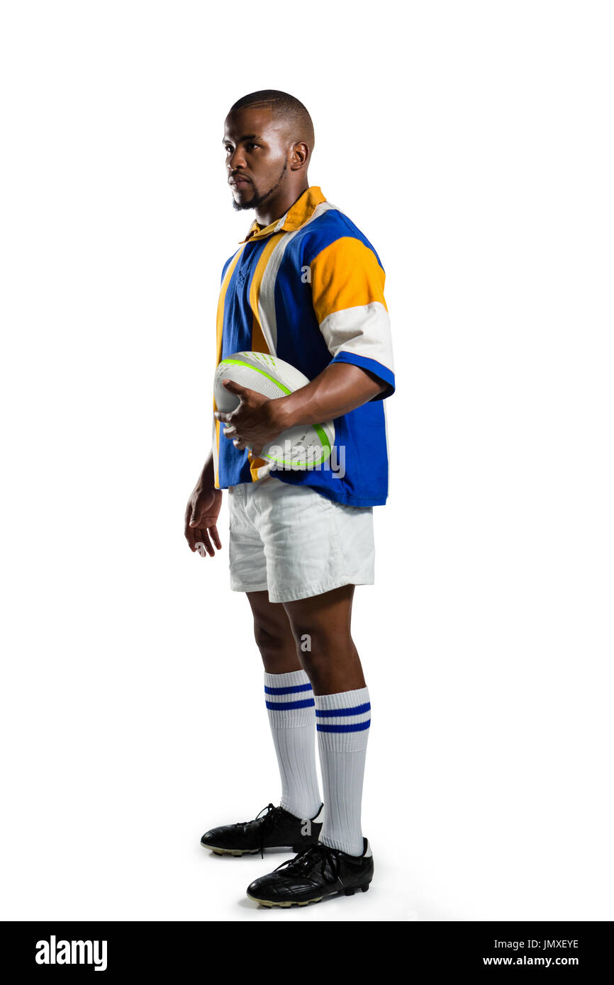Side view of confident rugby player holding ball against white ...
