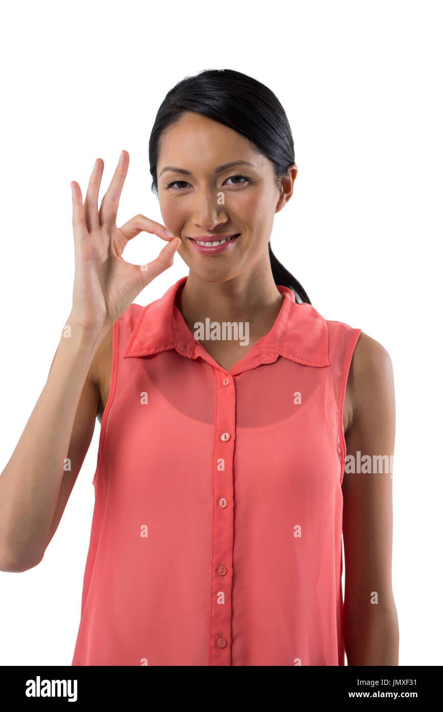 Portrait of smiling woman gesturing okay hand sign against white ...