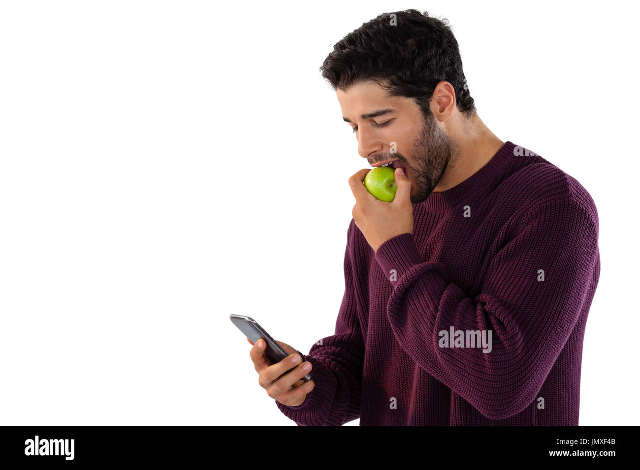 Man eating apple while using mobile phone against white background ...