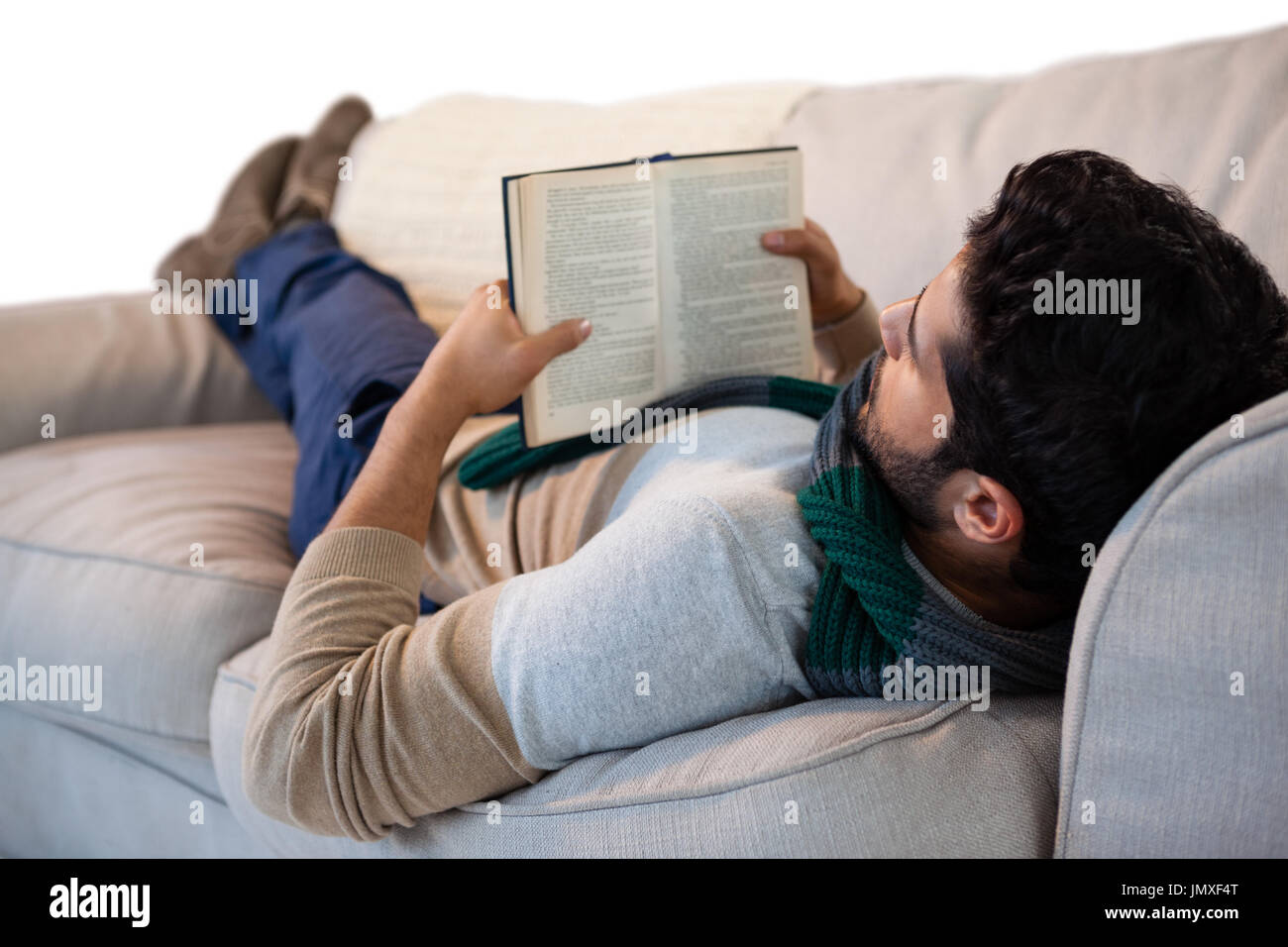 Man lying on sofa while reading book against white background Stock ...