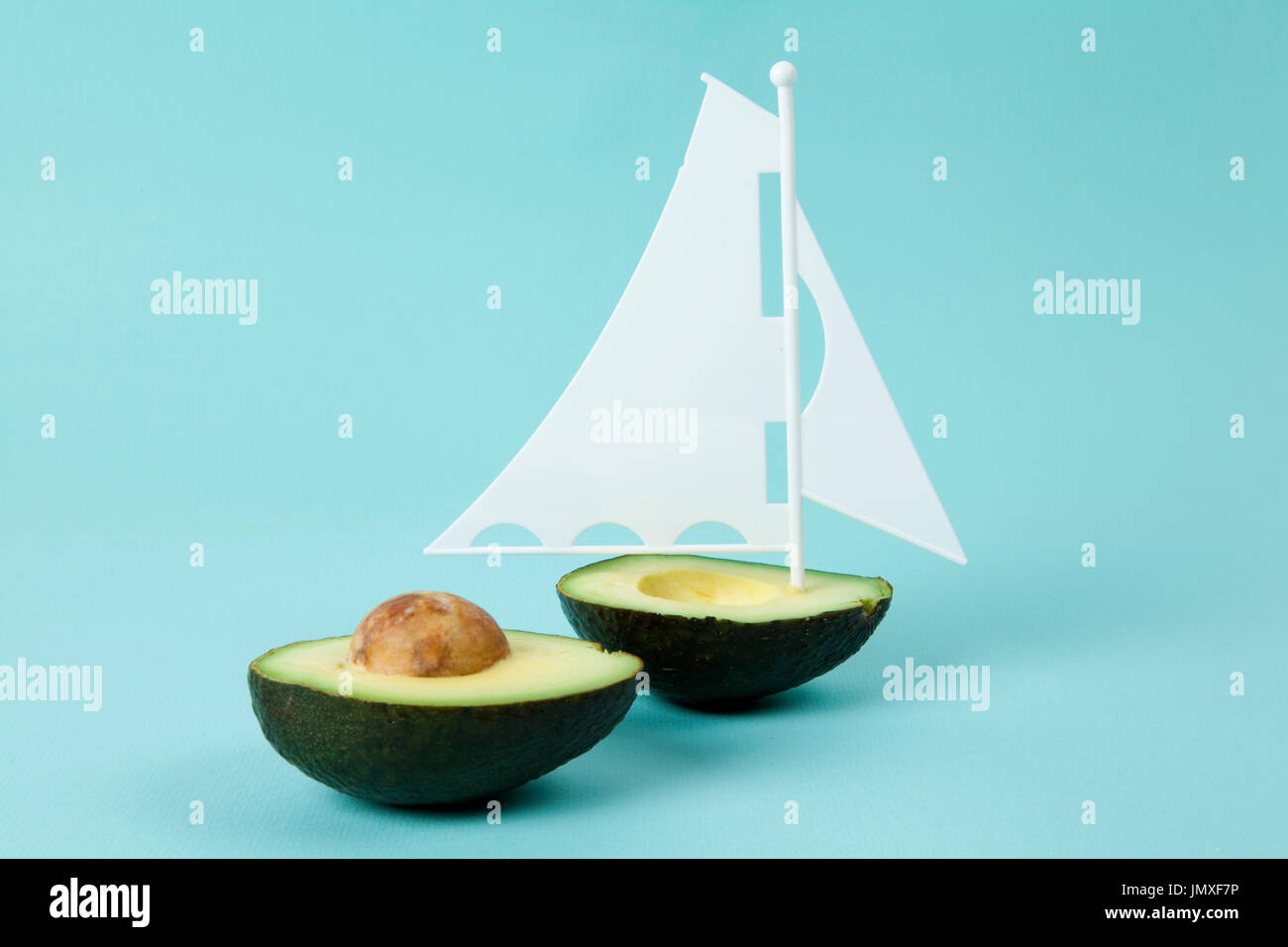 avocado half with white sail on a turquoise background. minimal and ...
