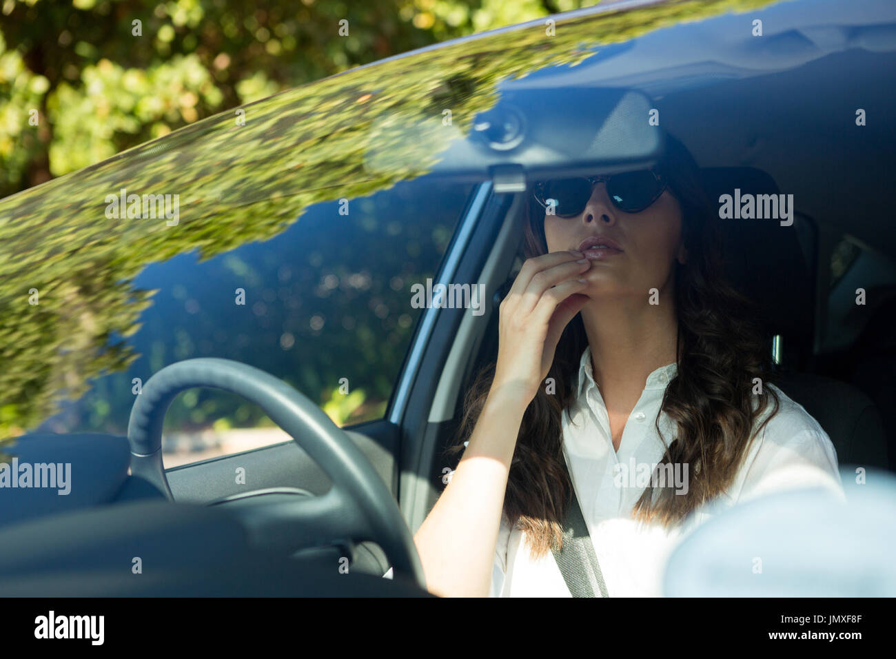 Beautiful woman looking into rear view mirror while driving a car Stock ...