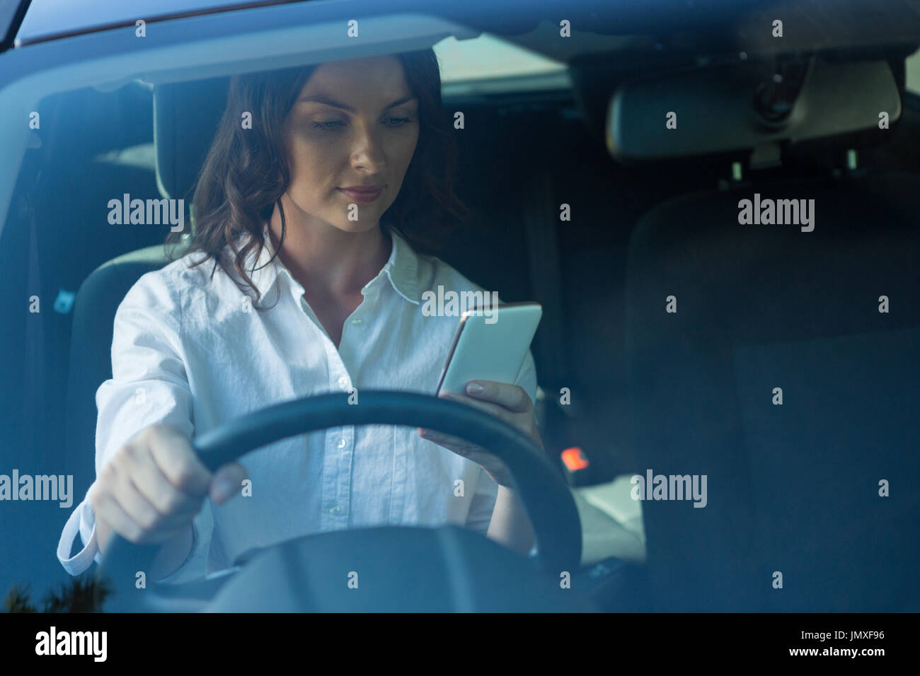 Beautiful woman using mobile phone while driving a car Stock Photo - Alamy