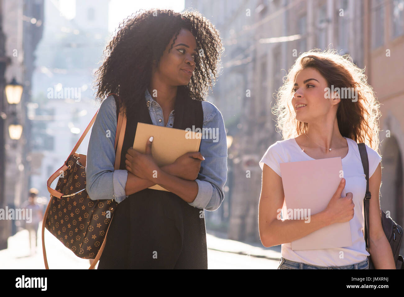 Two girls students walking and having conversation. Girls with books ...