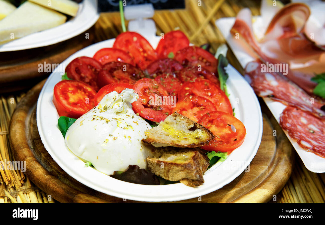 Traditional Italian platter with tomato, burata cheese, bread and bacon ...
