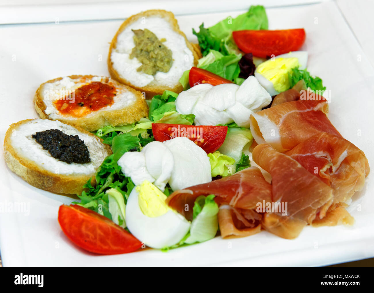 Traditional Italian platter with tomato, cheese, bread and prosciutto ...