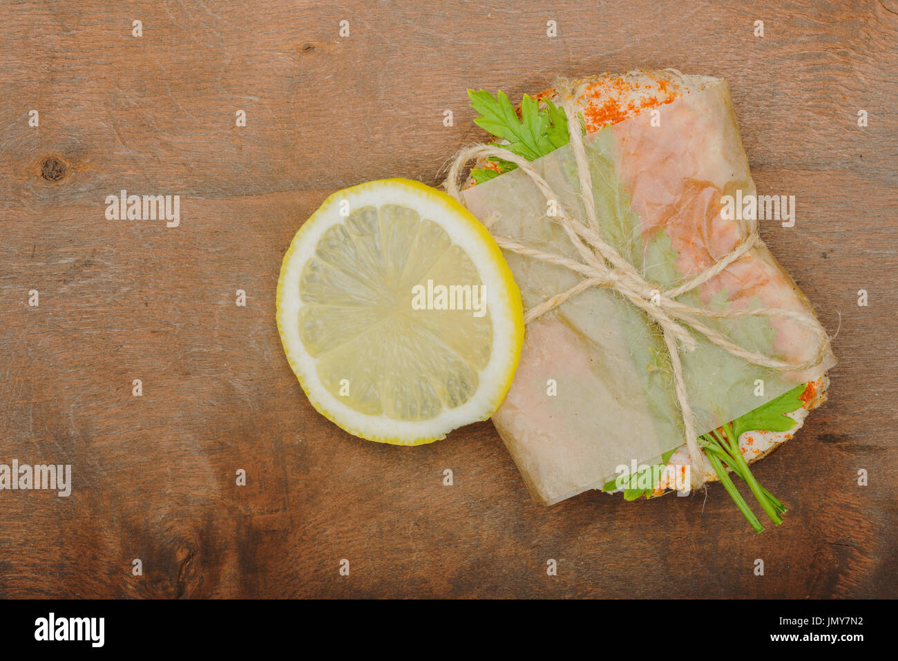 Sandwich wrapped in paper and tied with string on plywood abstract ...