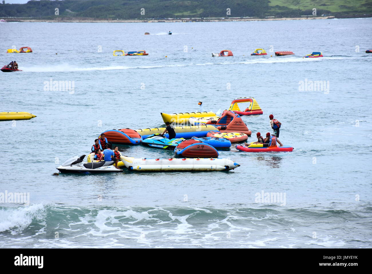 Some people enjoying the ocean and some inflatable boats for recreation ...