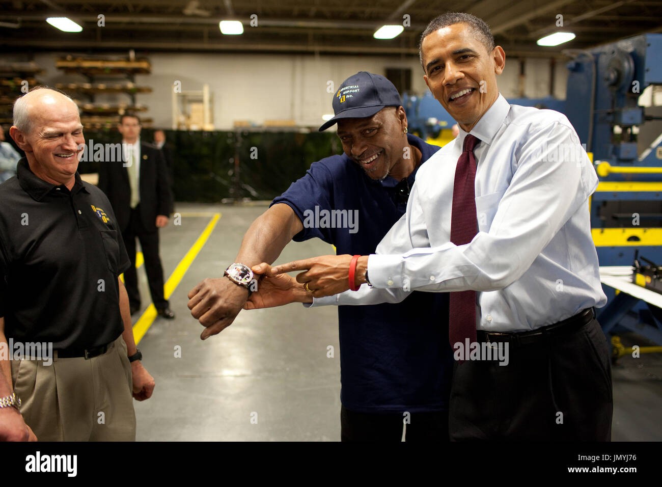 United States President Barack Obama points to an employee's watch with ...