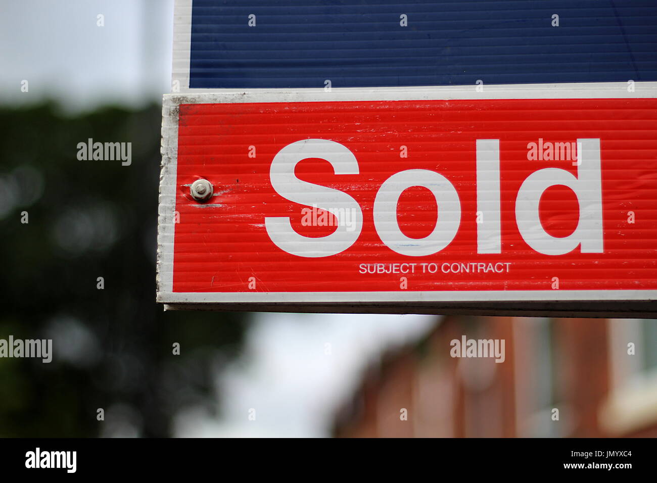 Estate agent sold sign with houses in background Stock Photo - Alamy