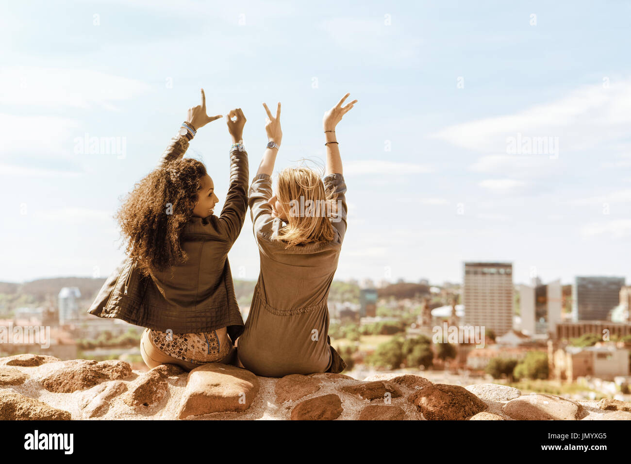 Two girls showing love sign using their fingers and enjoying the city ...