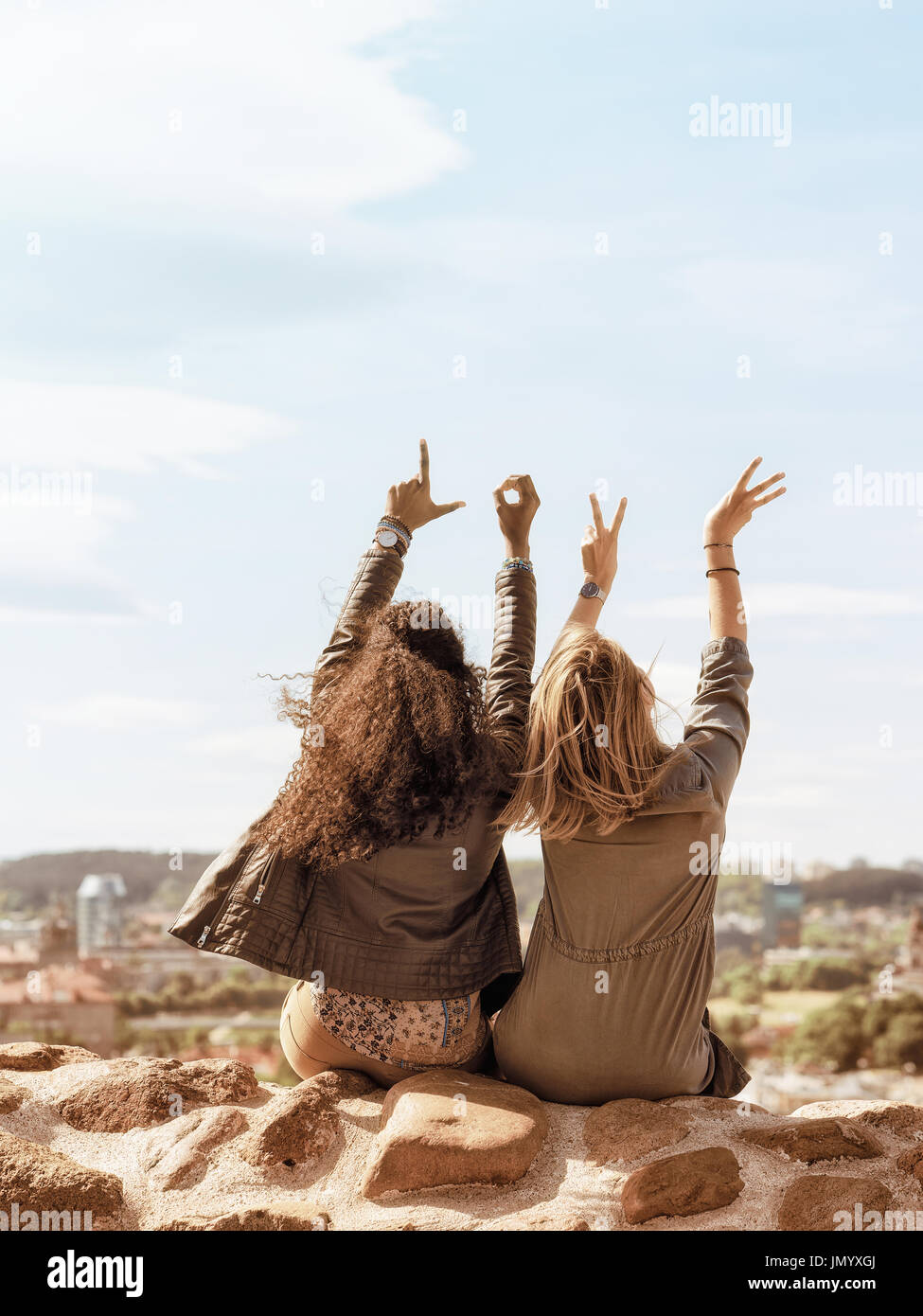 Two girls showing love sign with their fingers and enjoying the city ...