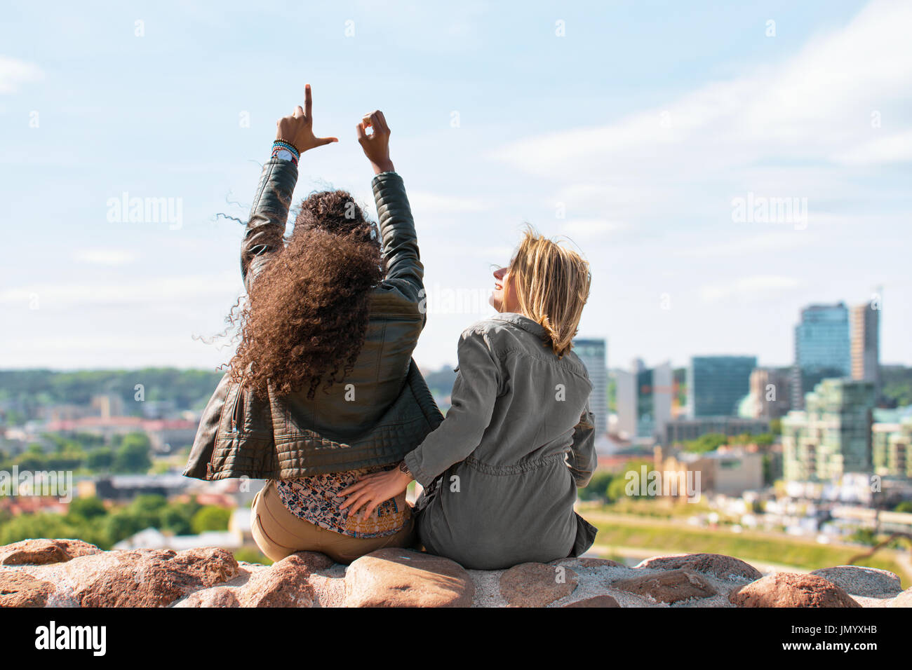 Two girls showing love sign with their fingers and enjoying the city ...