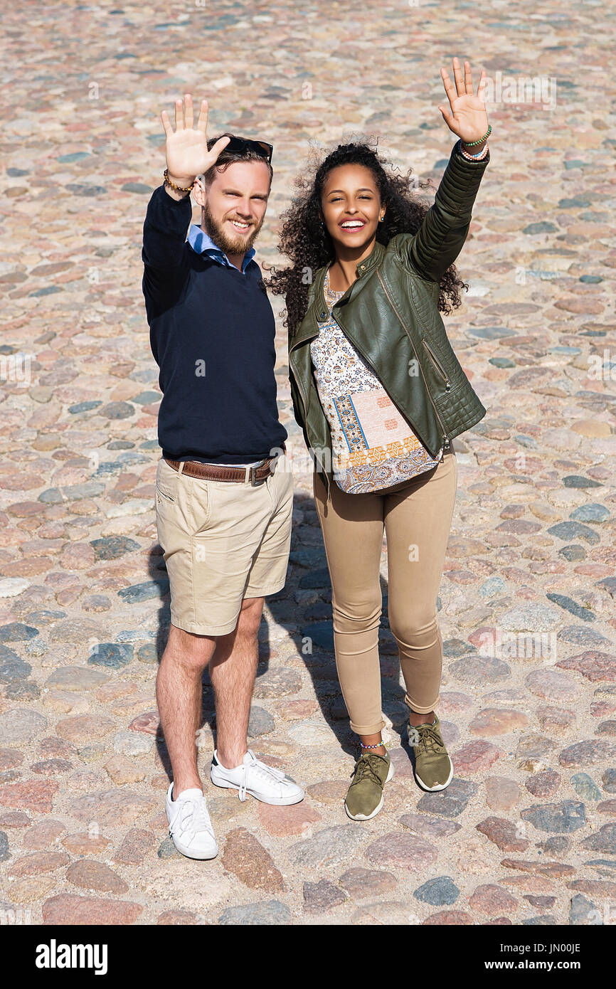 Young multiracial couple greeting friends as diversity friendship and ...