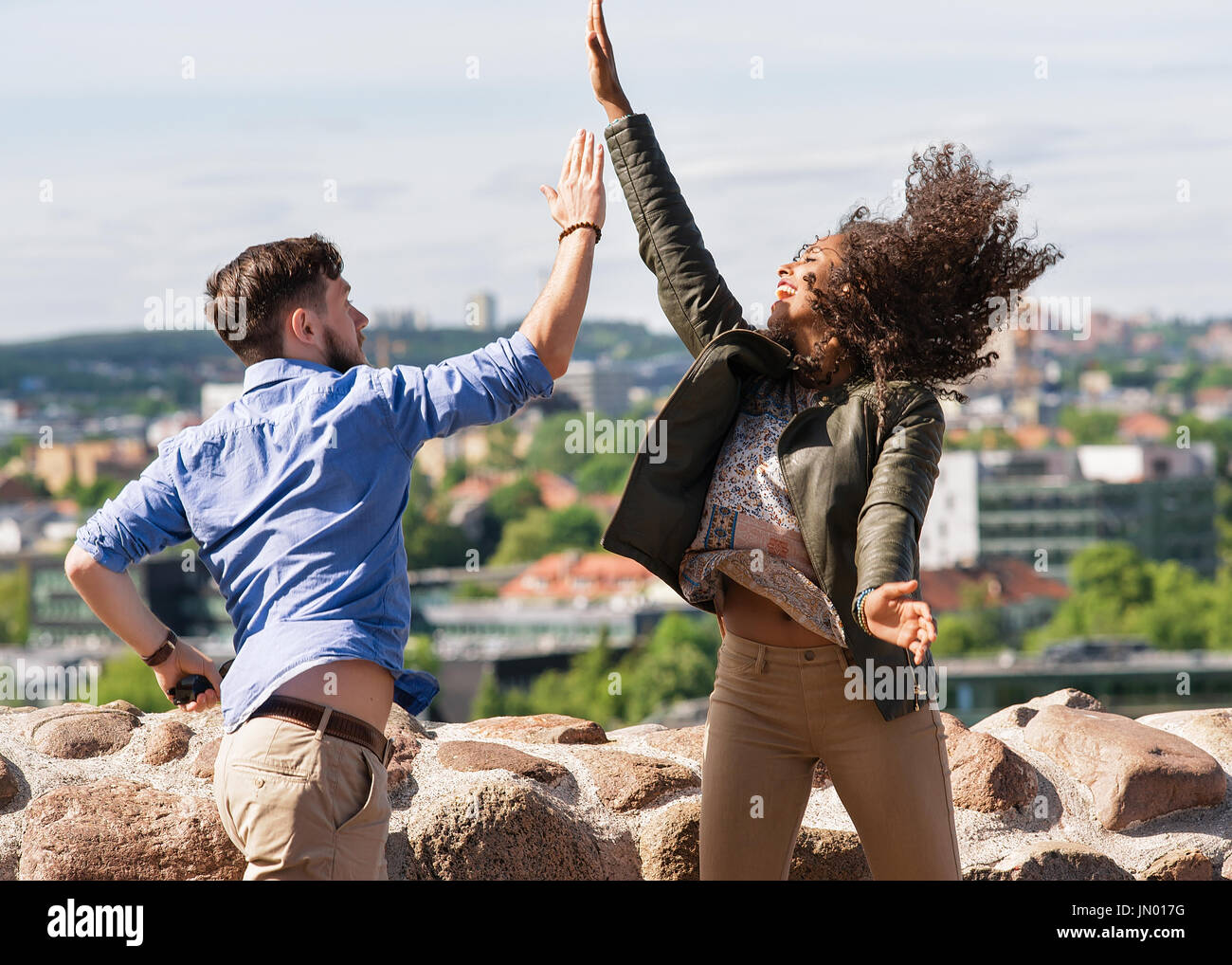 Young smiling multiracial couple having fun when clapping their hands ...