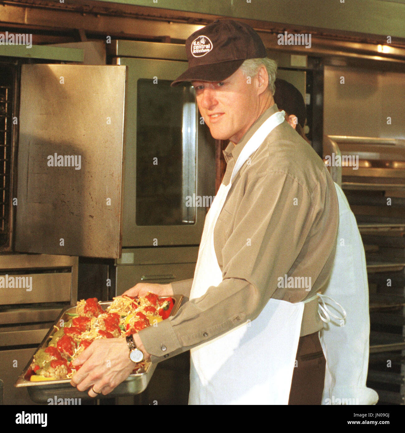 United States President Bill Clinton puts a tray of food in an oven at ...