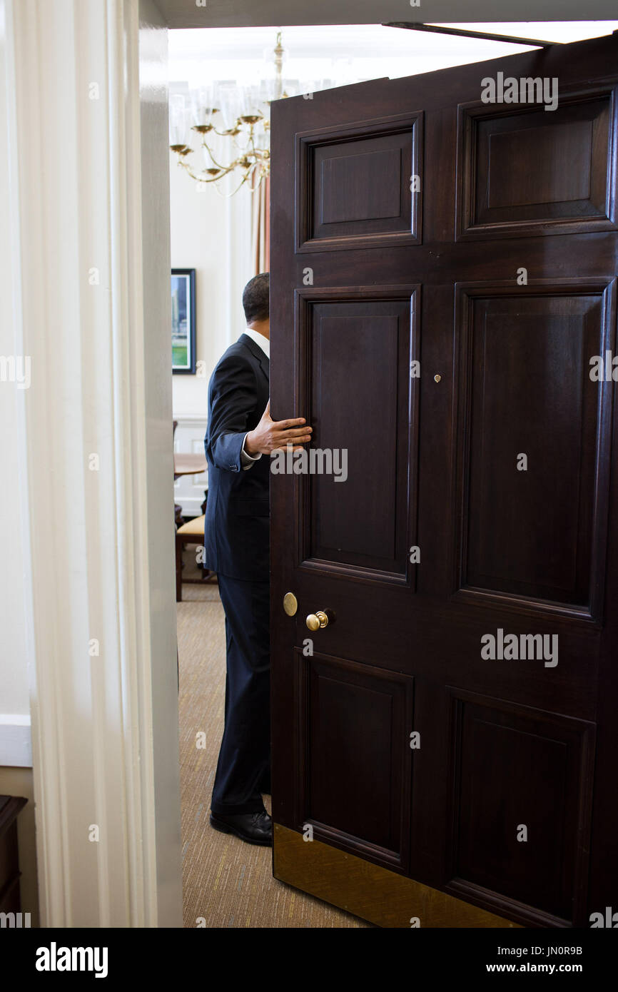 United States President Barack Obama holds the door while talking to ...