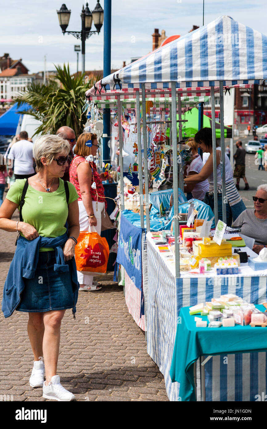 Open air market in bright sunshine at Ramsgate seafront. Mature woman ...