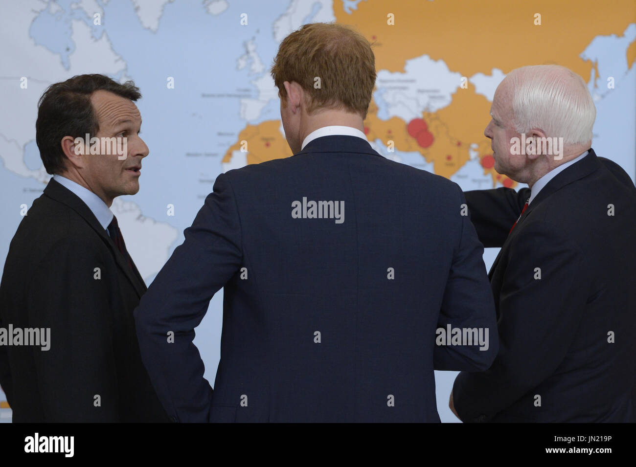 Prince Harry (C) of Wales stands in front of a world map while touring ...