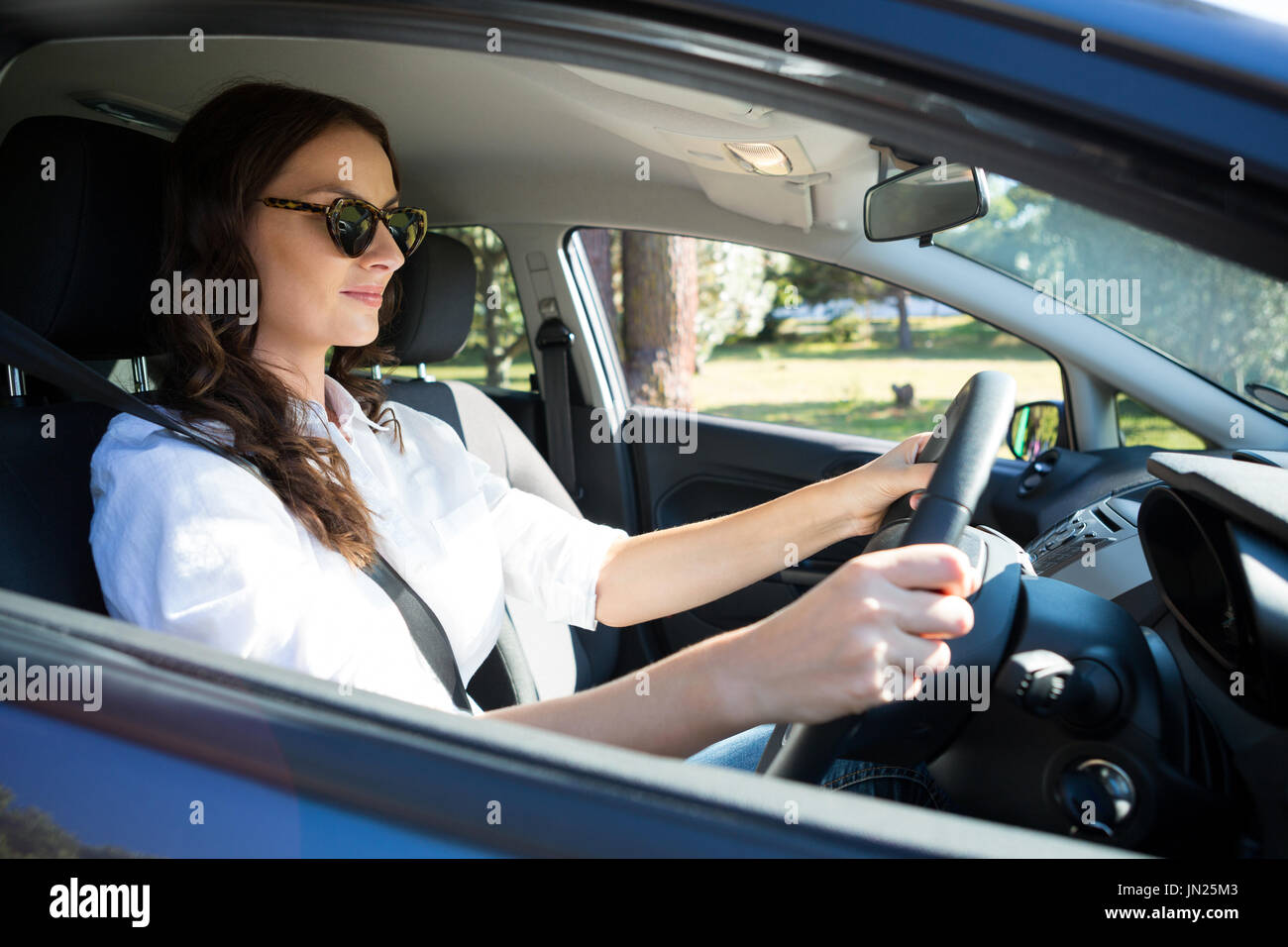 Active senior woman looking into rear view mirror while driving a car ...