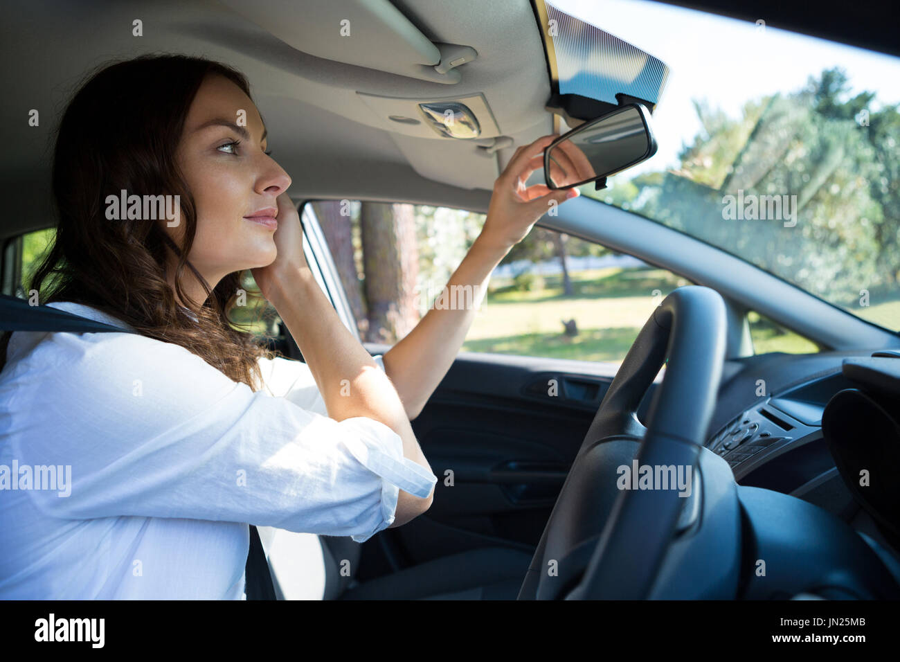 Beautiful woman looking into rear view mirror while driving a car Stock ...