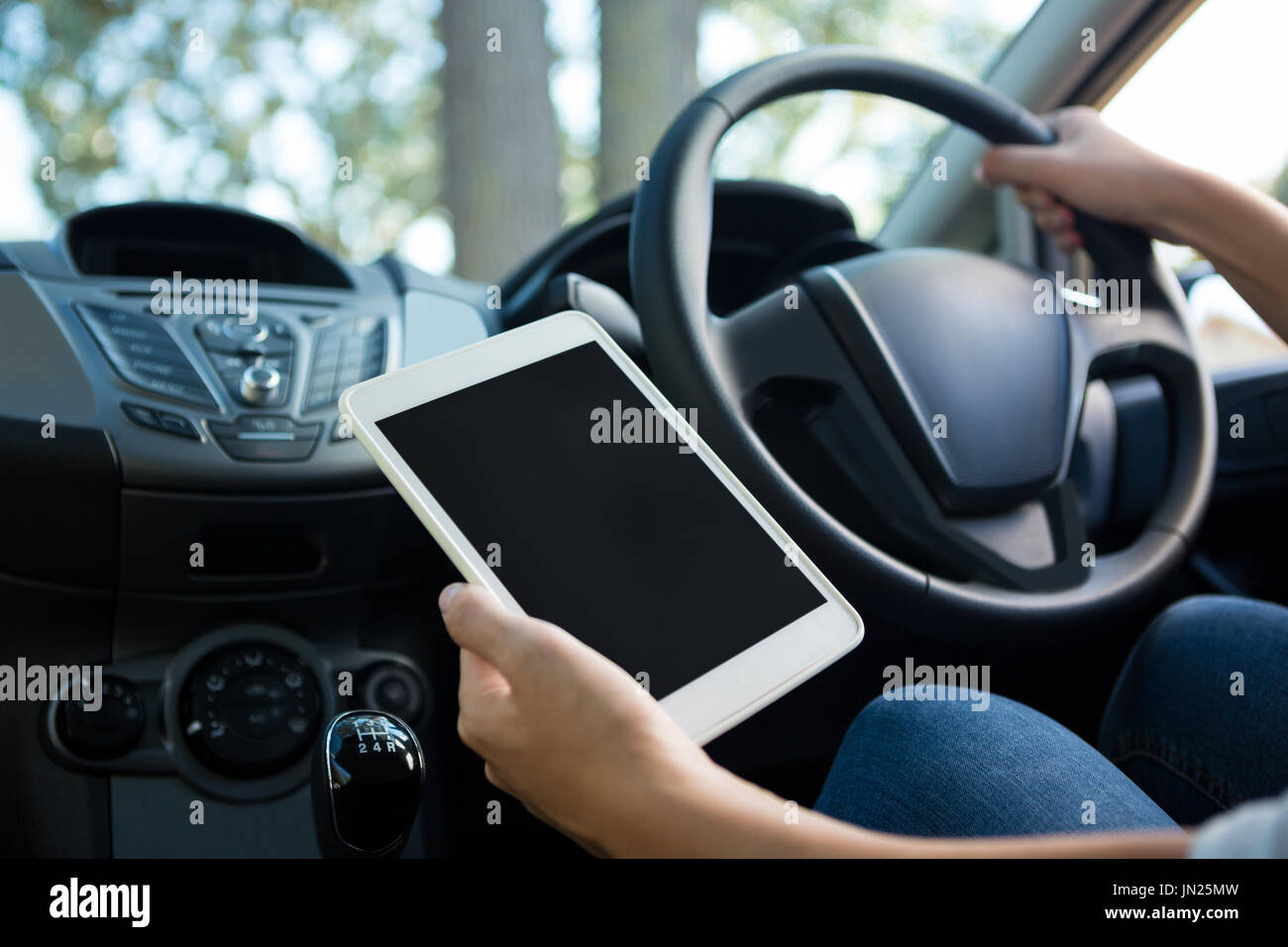 Mid-section of woman using digital tablet while driving a car Stock ...