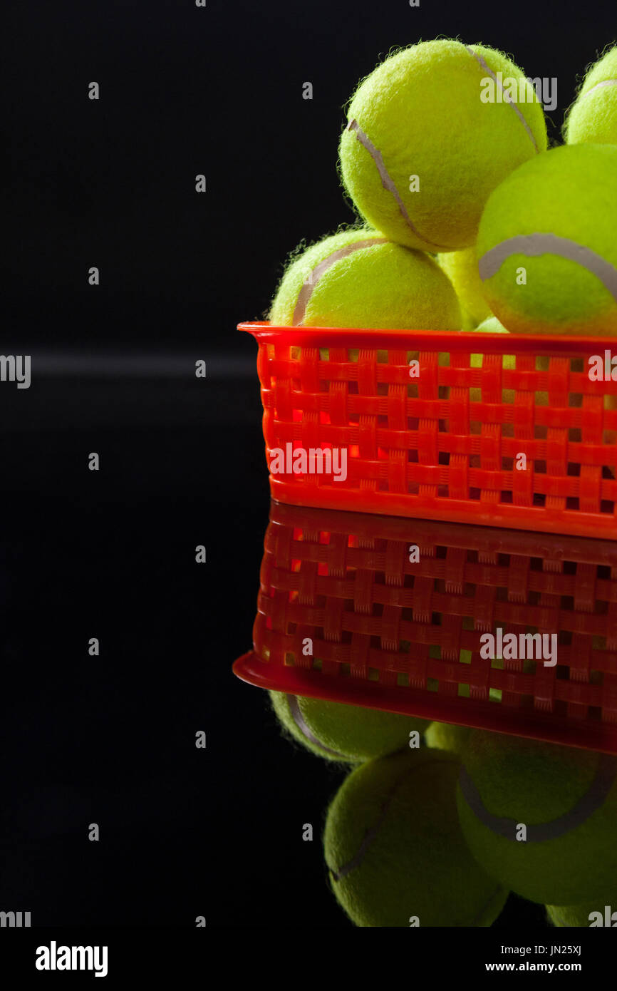 Close up of fluorescent yellow tennis balls in plastic basket with ...