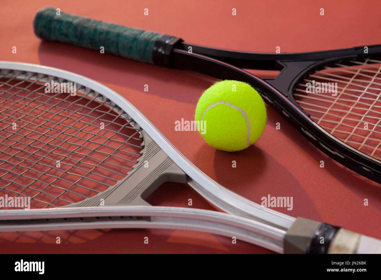High angle view of fluorescent yellow ball amidst tennis rackets on ...