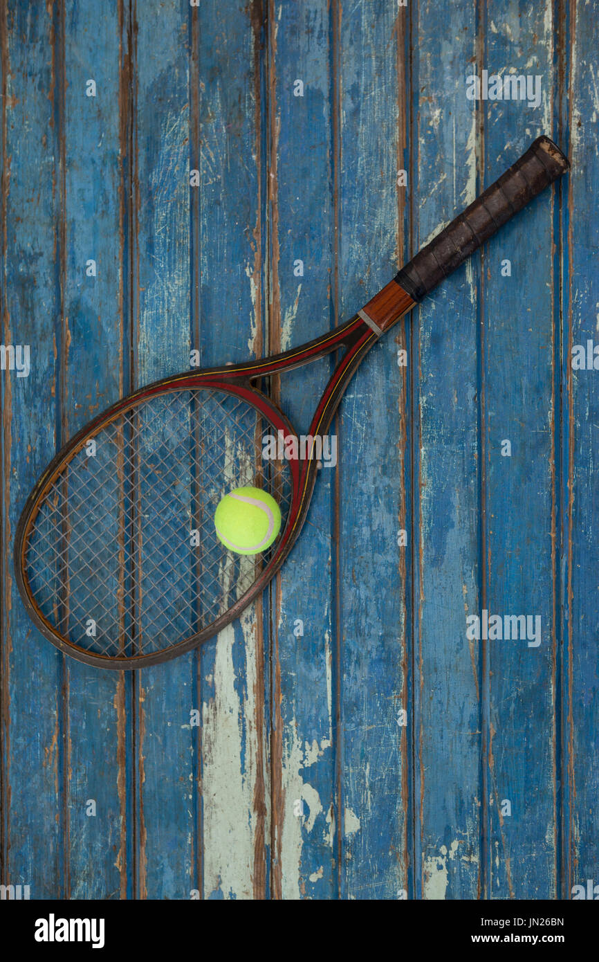 Overhead view of brown tennis racket with ball on blue wooden table ...