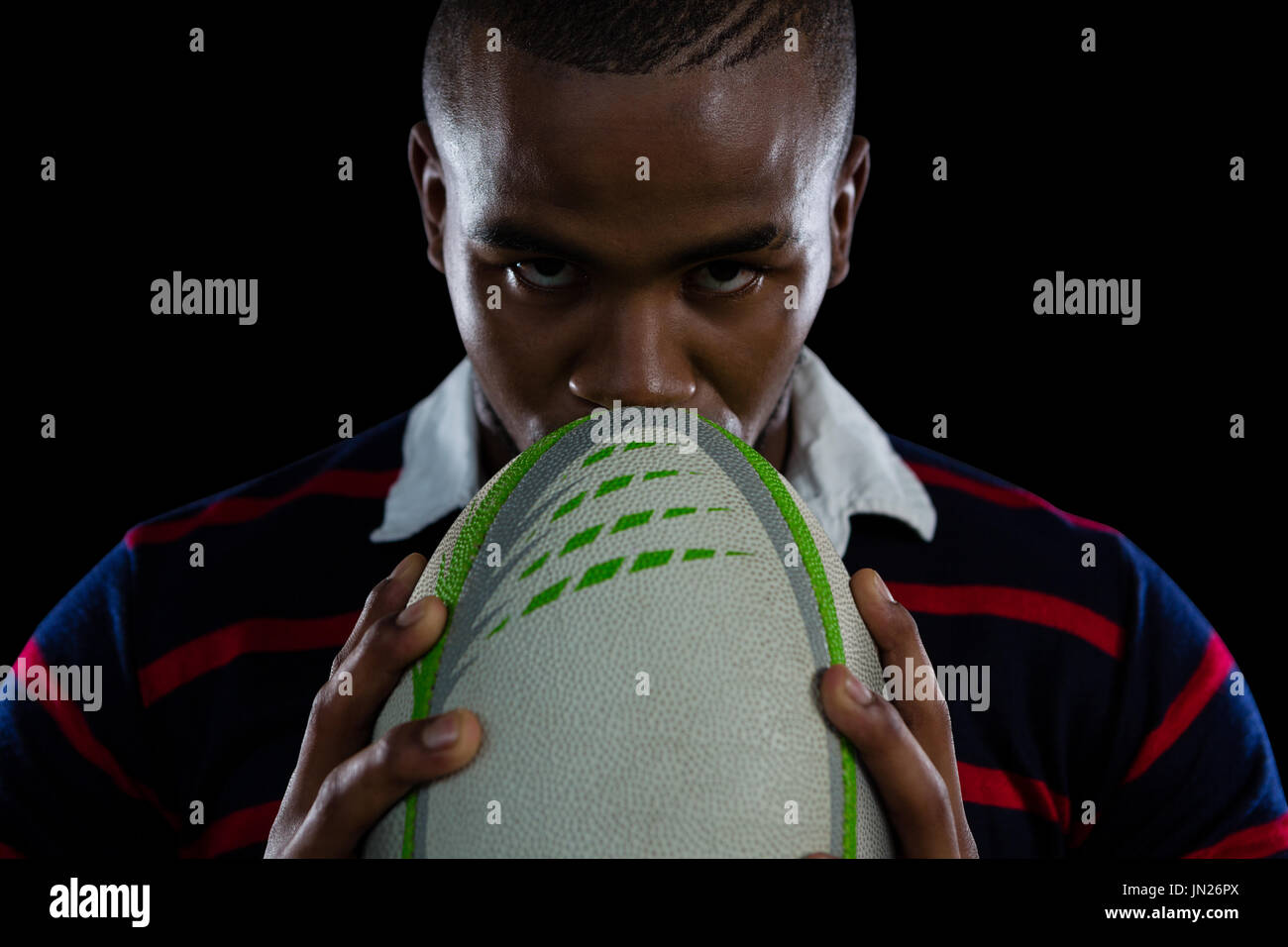 Close up portrait of male rugby player with ball against black ...