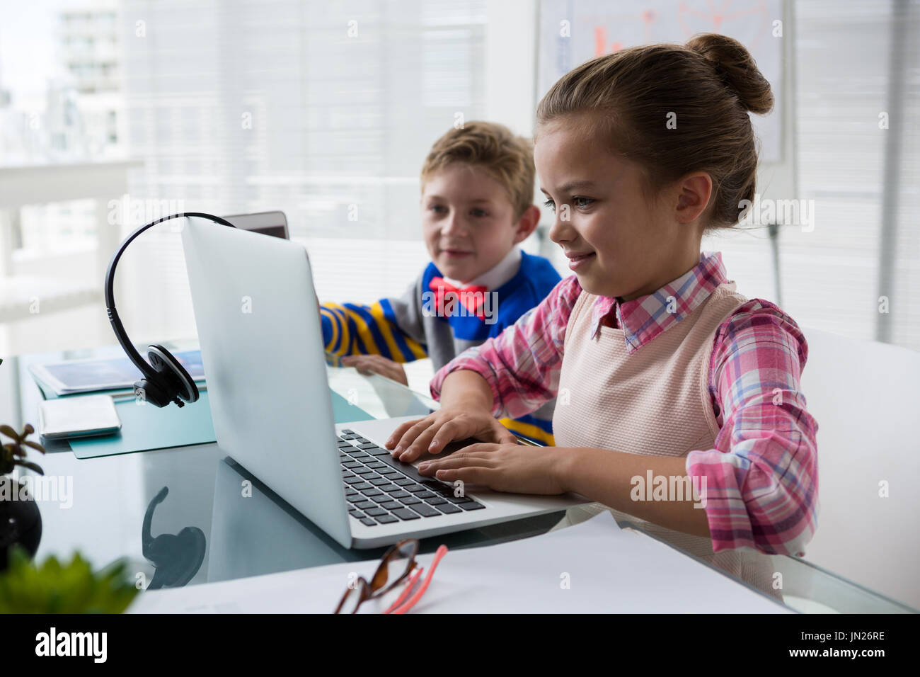 Kids as business executive interacting while using laptop in office ...
