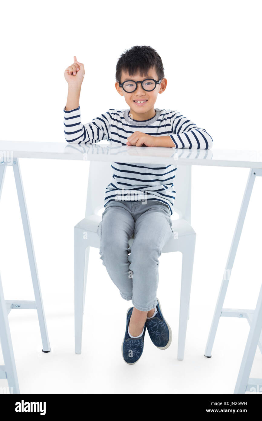 Portrait of boy sitting on chair against white background Stock Photo ...